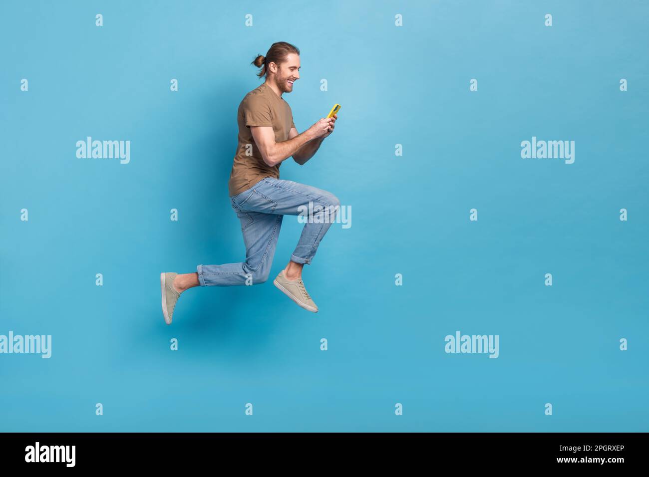 Full length photo of excited pretty guy dressed t-shirt jumping typing ...