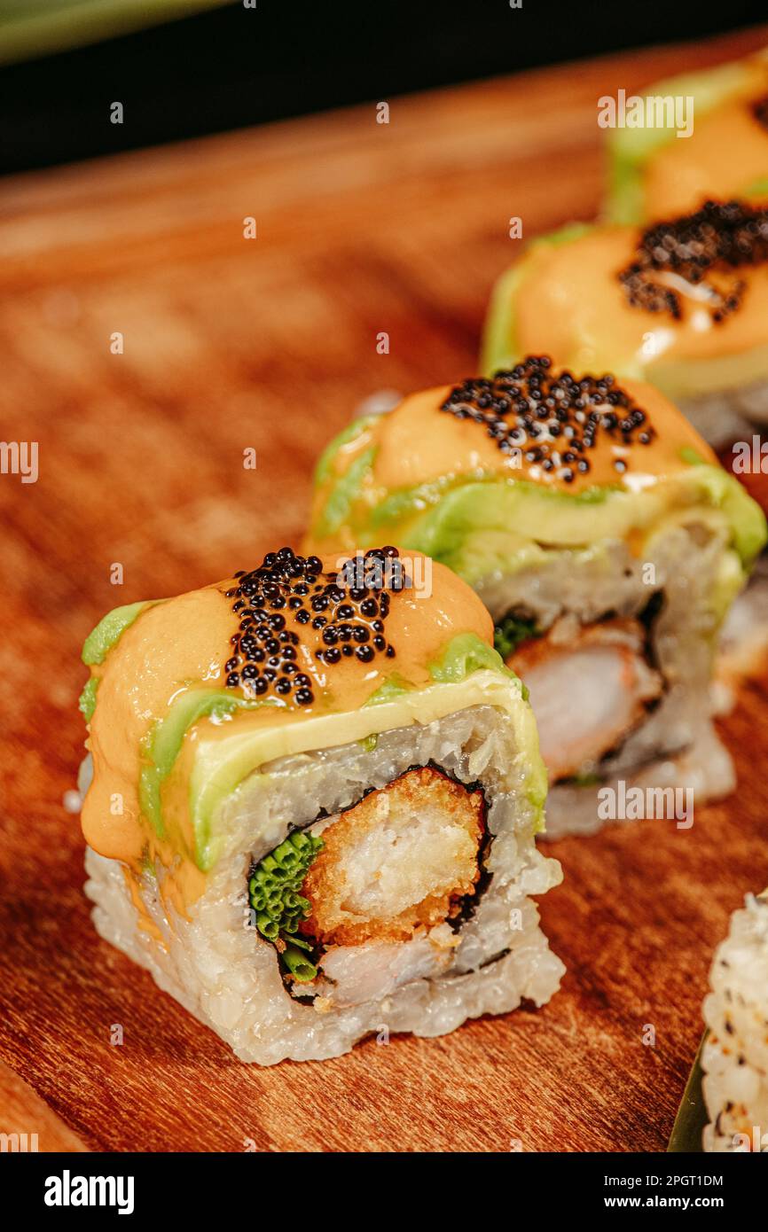 A wooden table with a variety of colorful sushi dishes, including maki ...