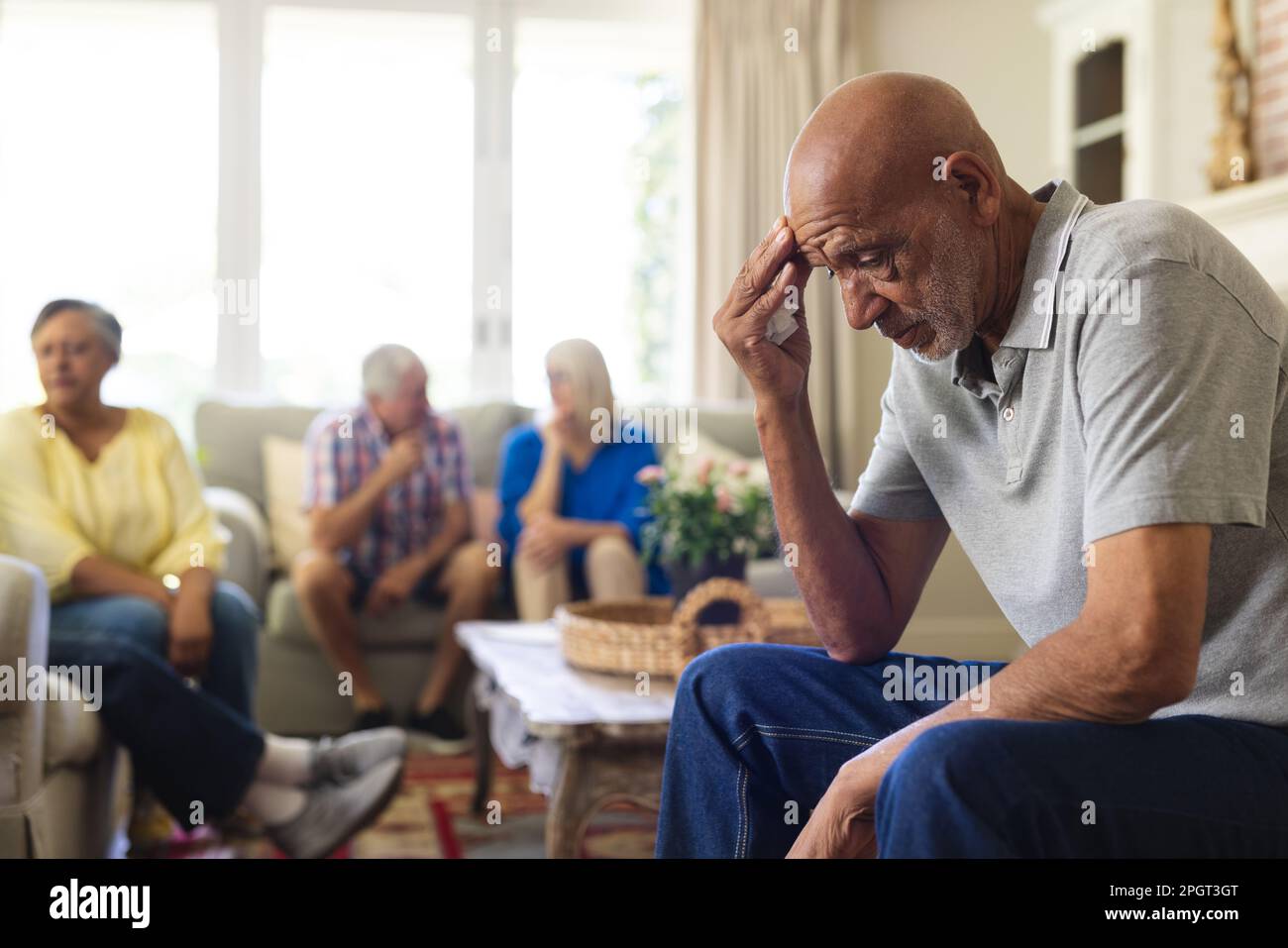 Group of emotional, diverse senior friends in living room, talking ...