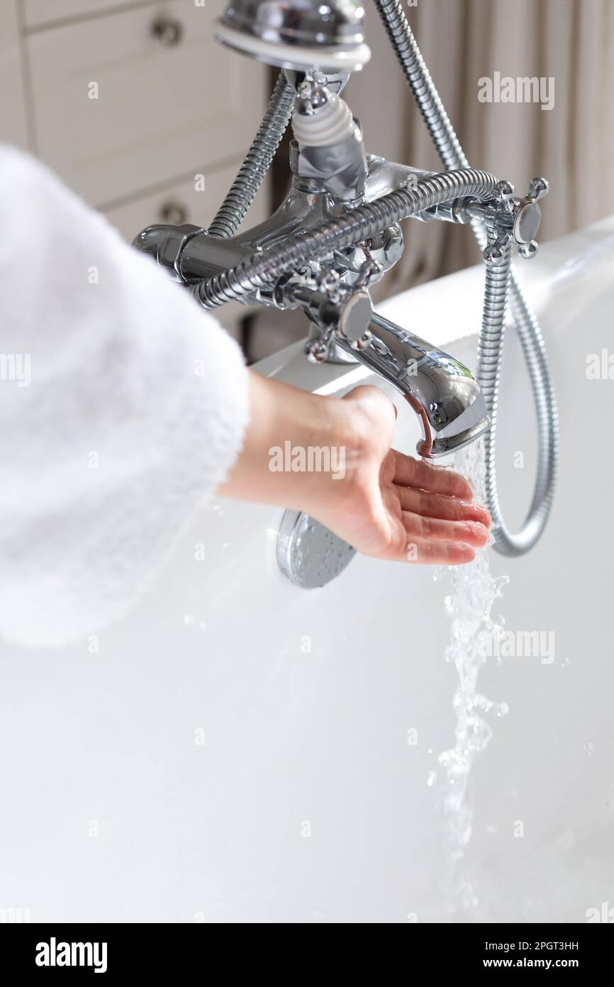 Hand of asian woman wearing bathrobe running bath in bathroom, copy ...