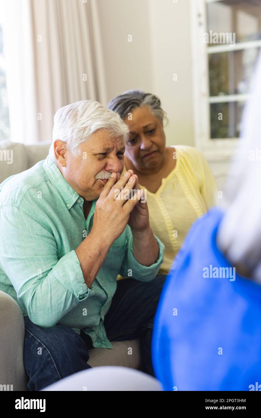 Sad group of diverse senior friends sitting in living room, listening ...