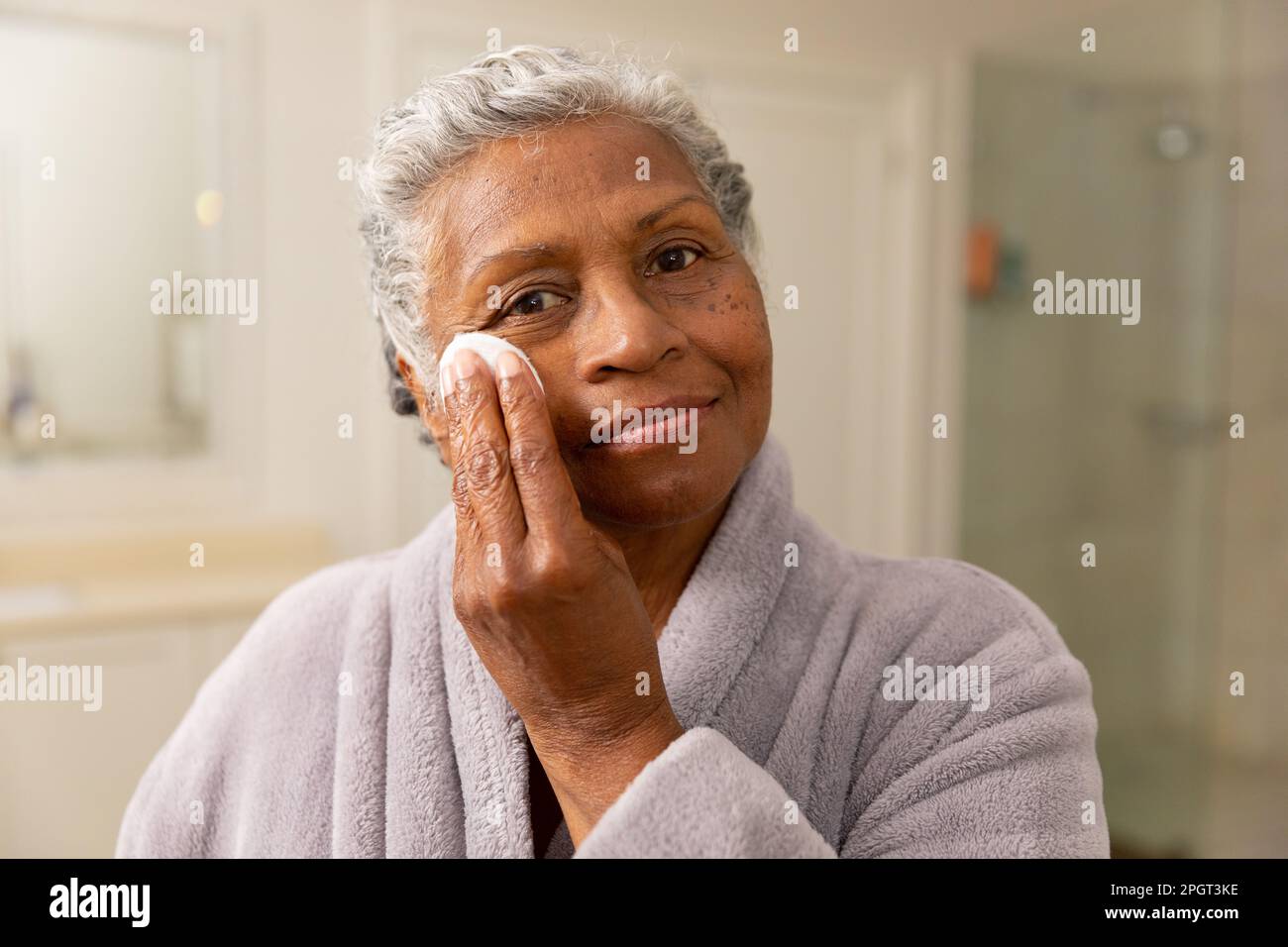 Closeup of african american senior woman dressed in bathrobe wiping ...