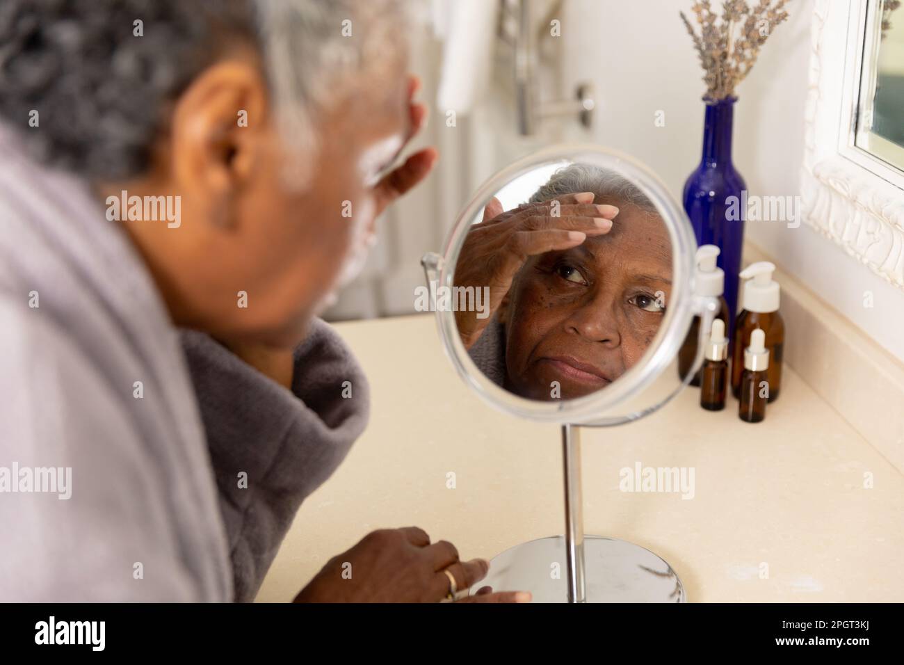 African american senior woman touching her face and checking blemishes ...