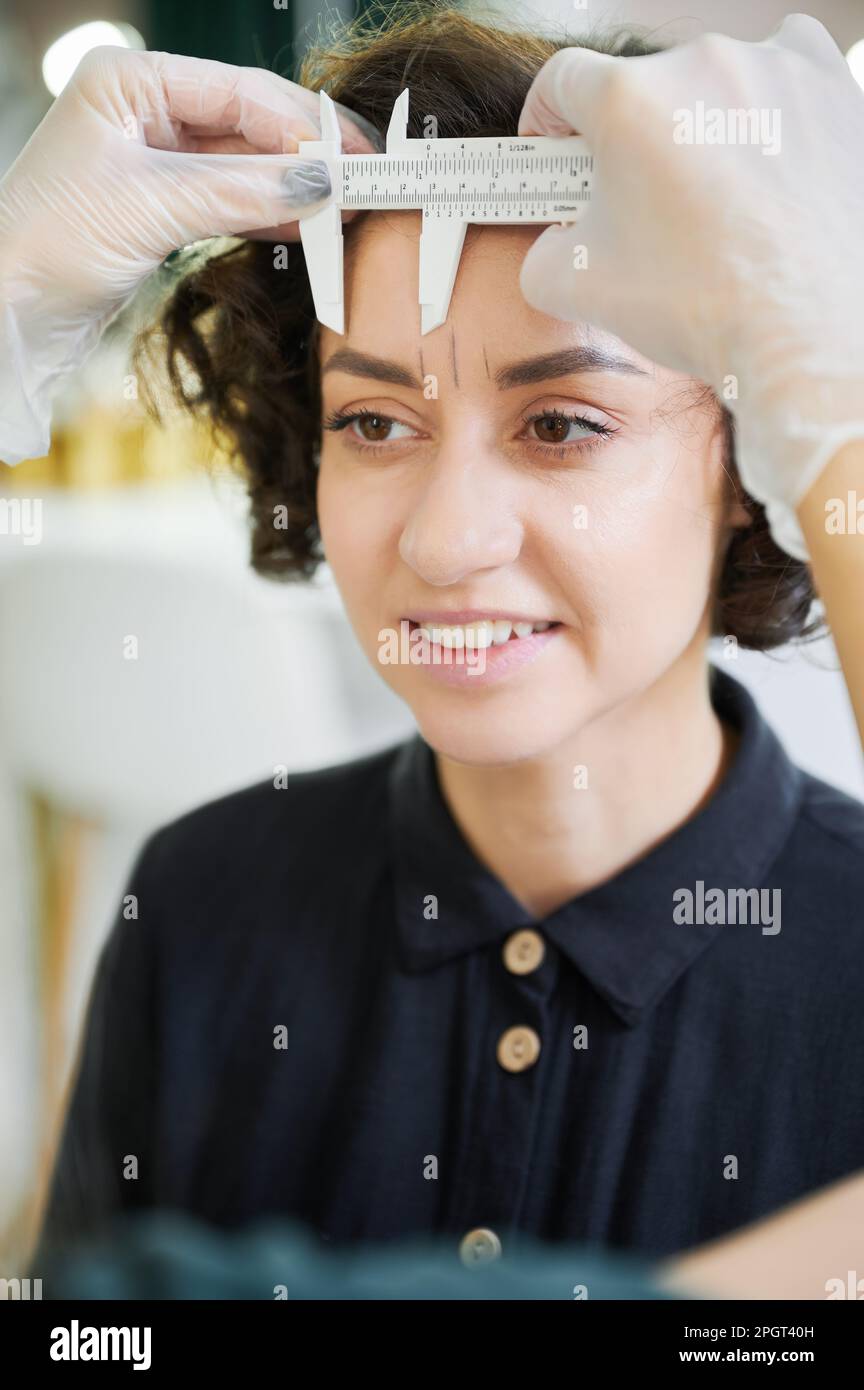 Esthetician using measuring tool for brow correction procedure in ...