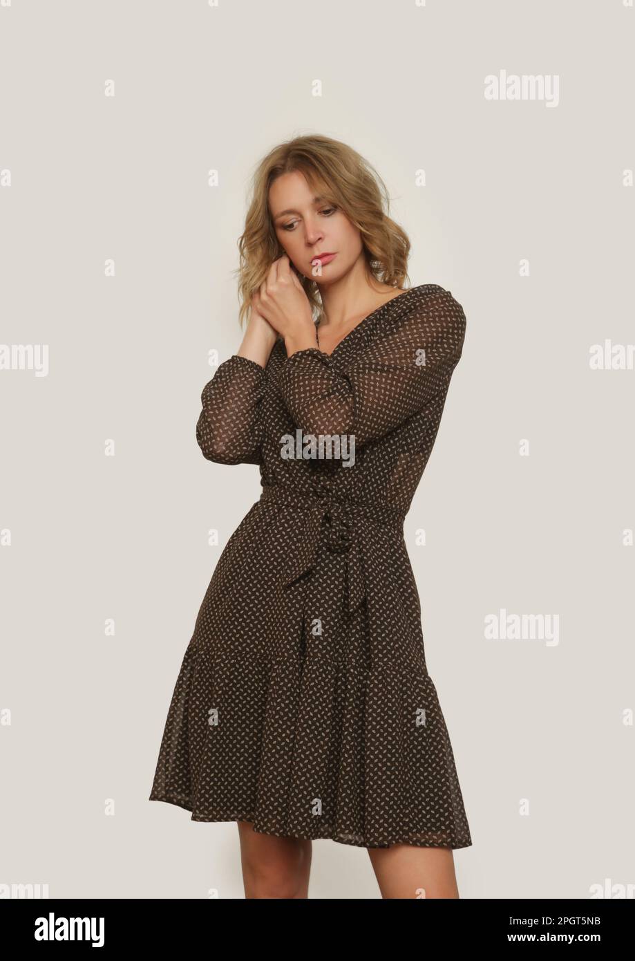 Serie of studio photos of young female model in brown patterned dress ...