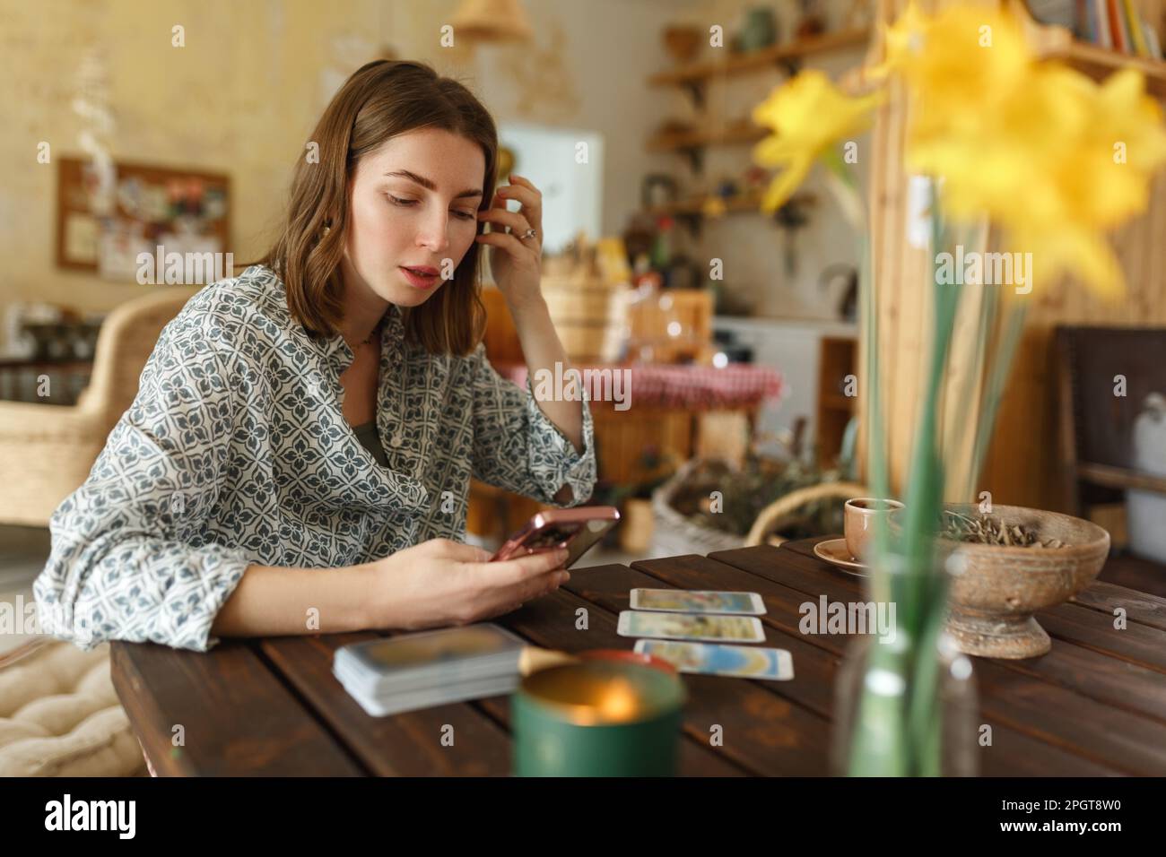 Beautiful young woman is guessing on cards with tarot, runes on wooden ...