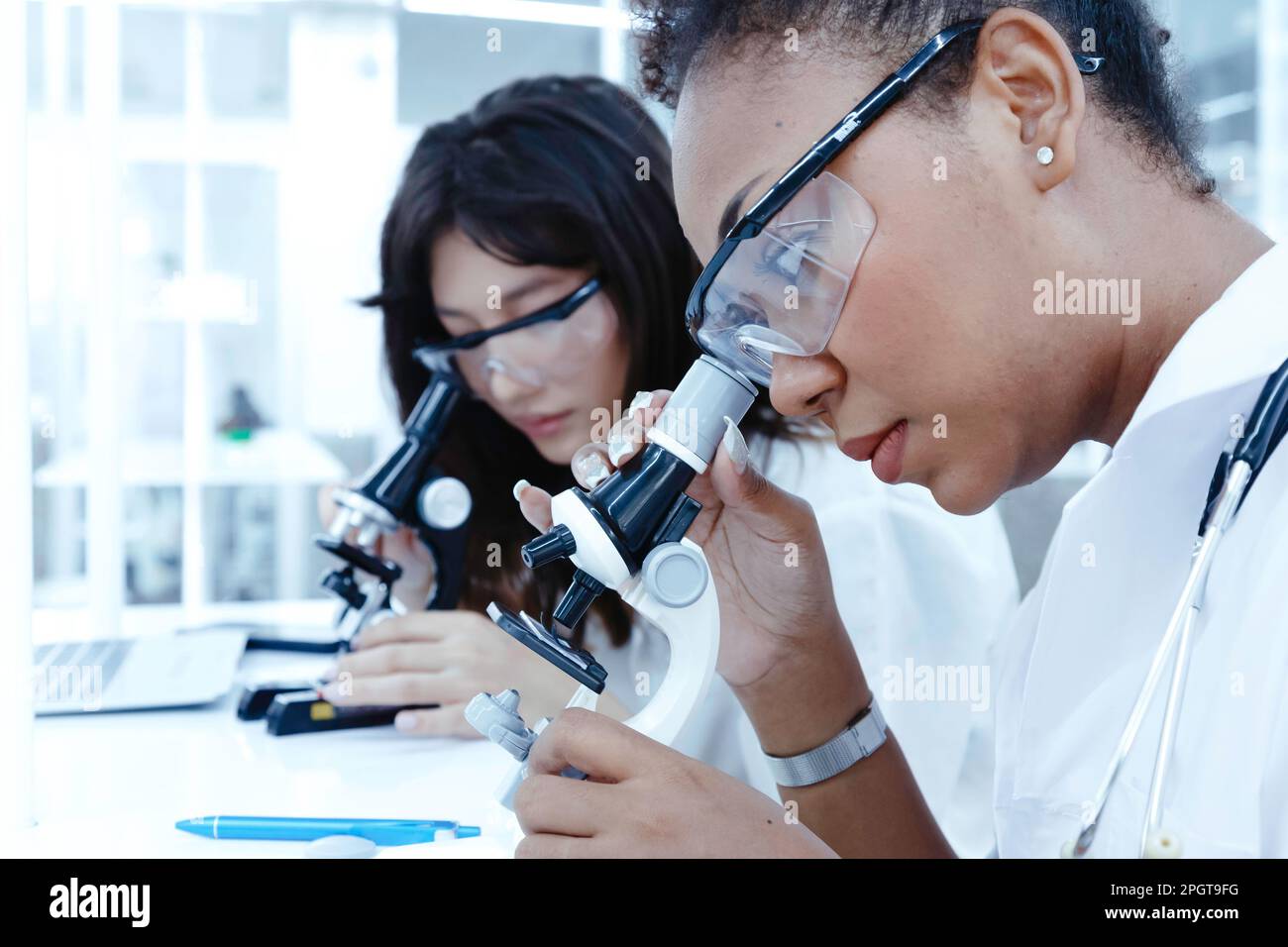 Two female doctor student scientist looking microscope does analysis ...