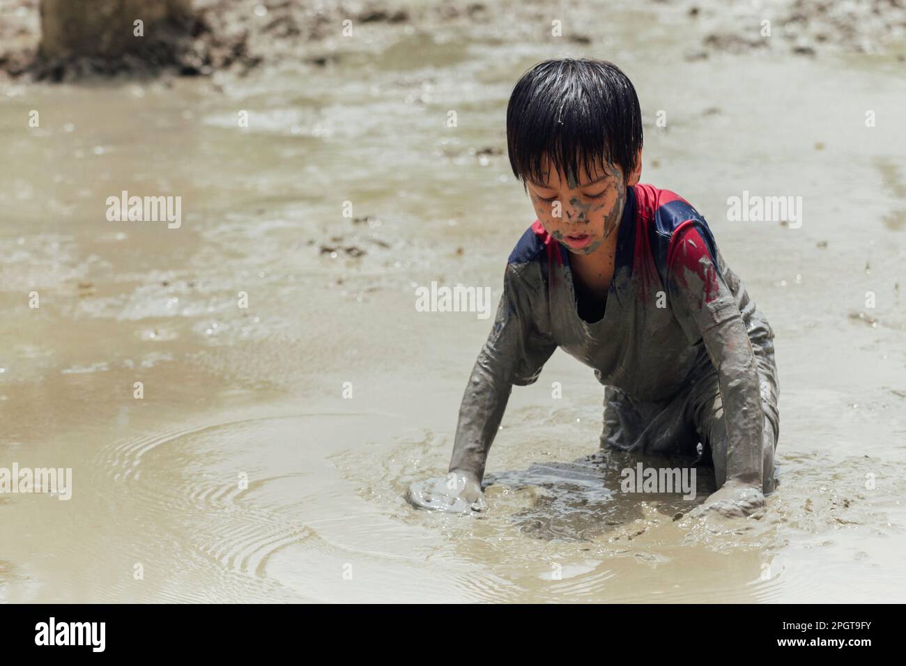 cute happy asian little boy enjoying to play in the mud at playground ...