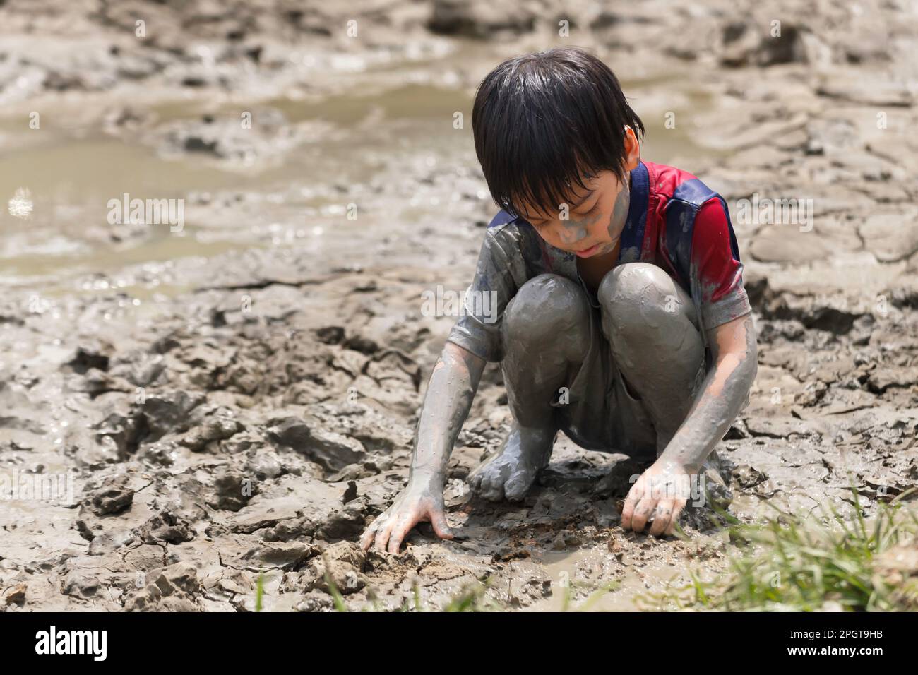 cute happy asian little boy enjoying to play in the mud at playground ...