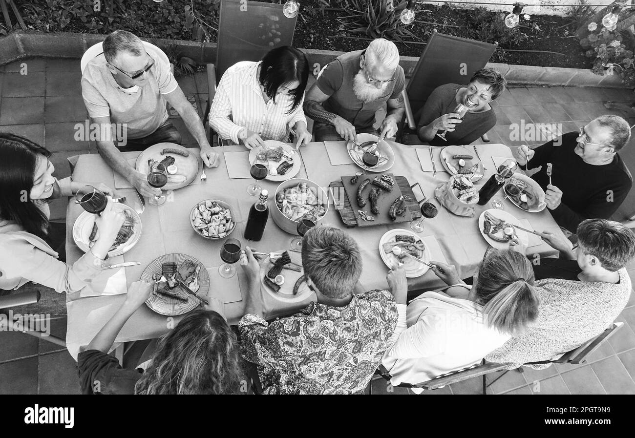 Multiracial family people eating at barbecue dinner at patio terrace ...