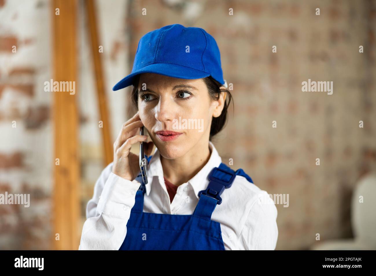 Female builder talking on phone with owner of building under renovation ...