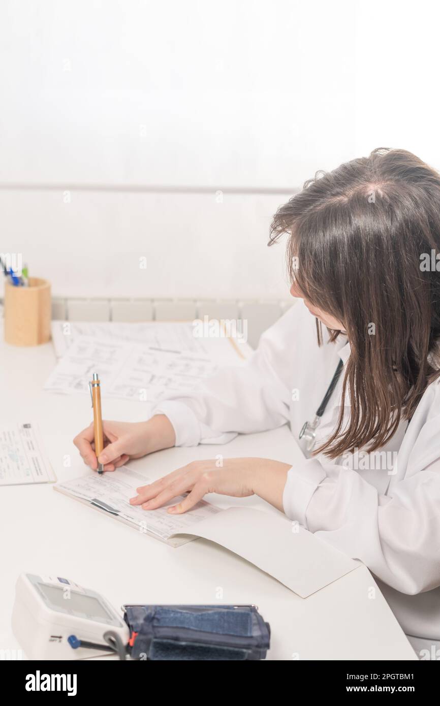 woman doctor writing a prescription to her patient at the doctor's ...