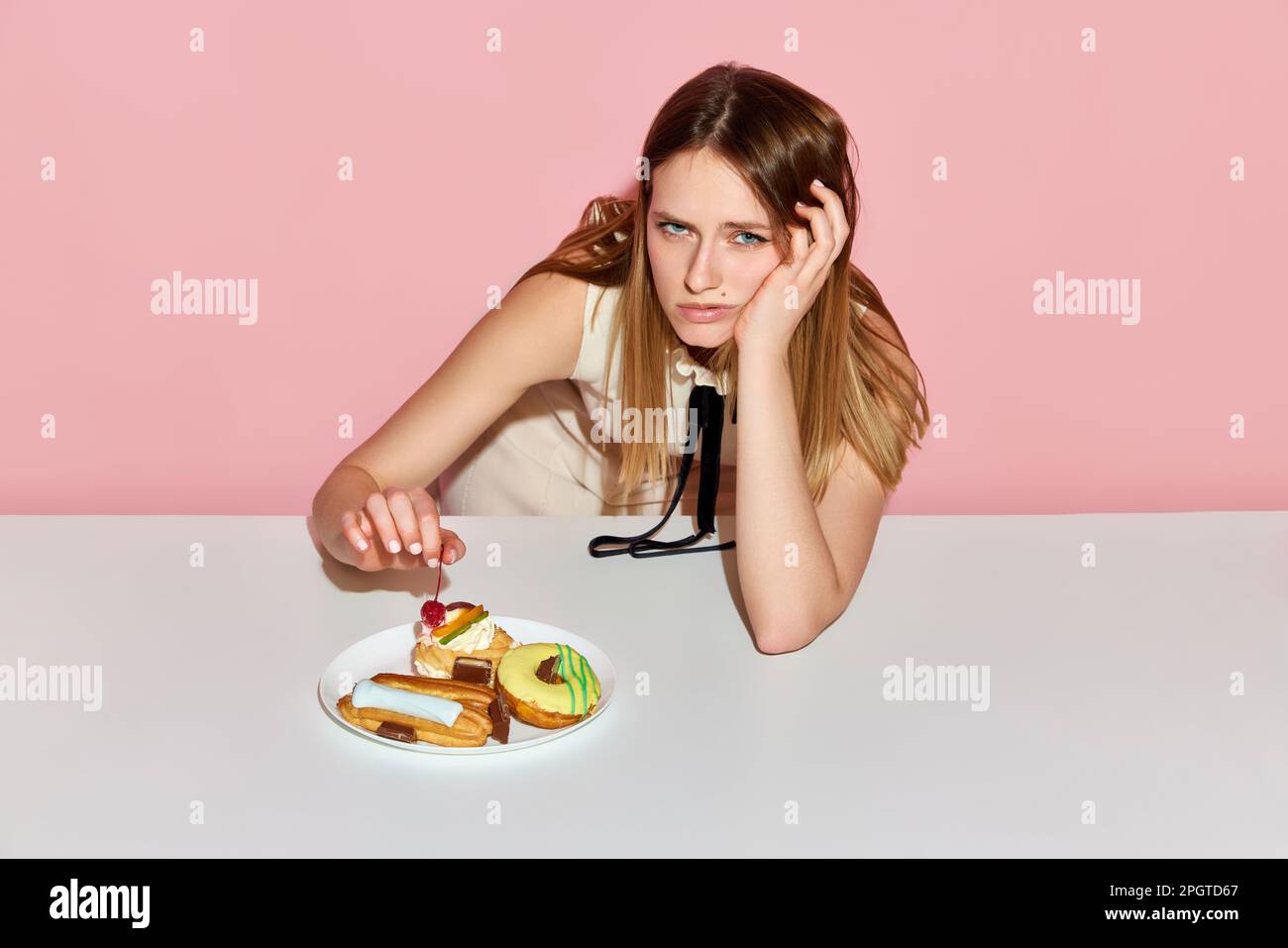 Upset young model surrounded by junk food looking at camera with sad ...