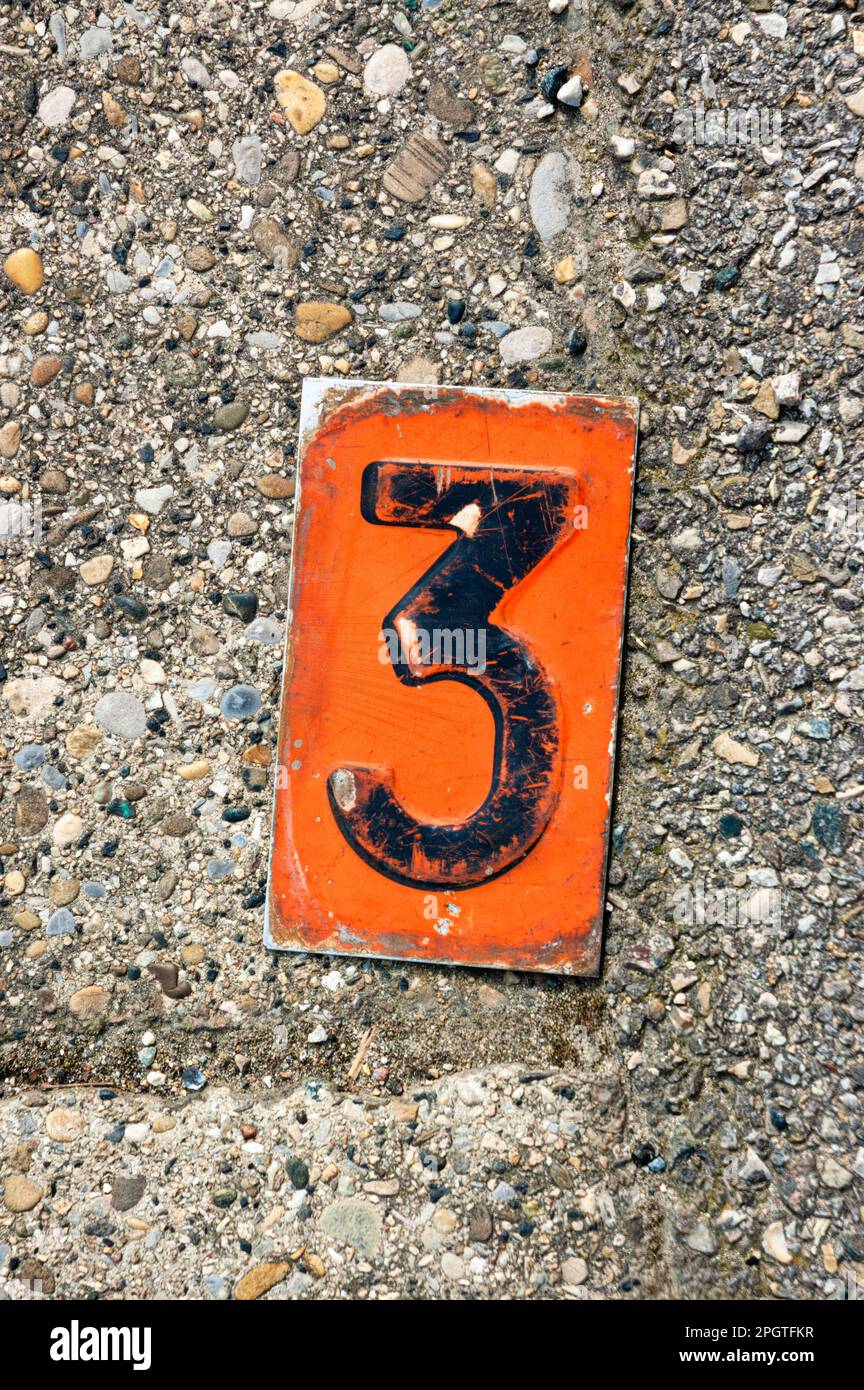 Number 3 on a metal orange plate, laying on the floor Stock Photo - Alamy
