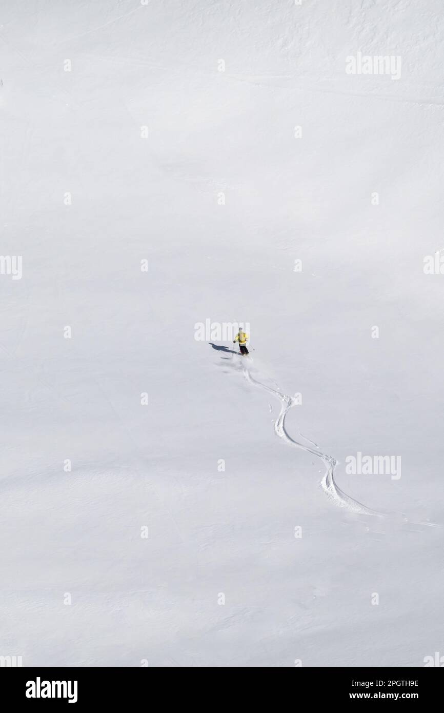 Single freeriding skier making fresh first tracks in recent powder snow ...