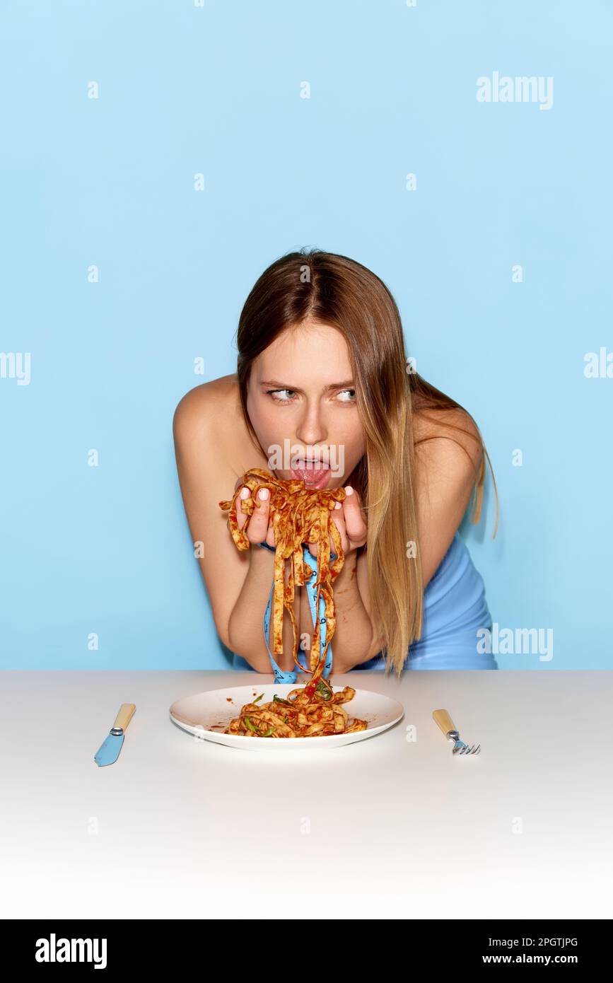 One young pretty girl with greedy face eating noodles by hands over ...