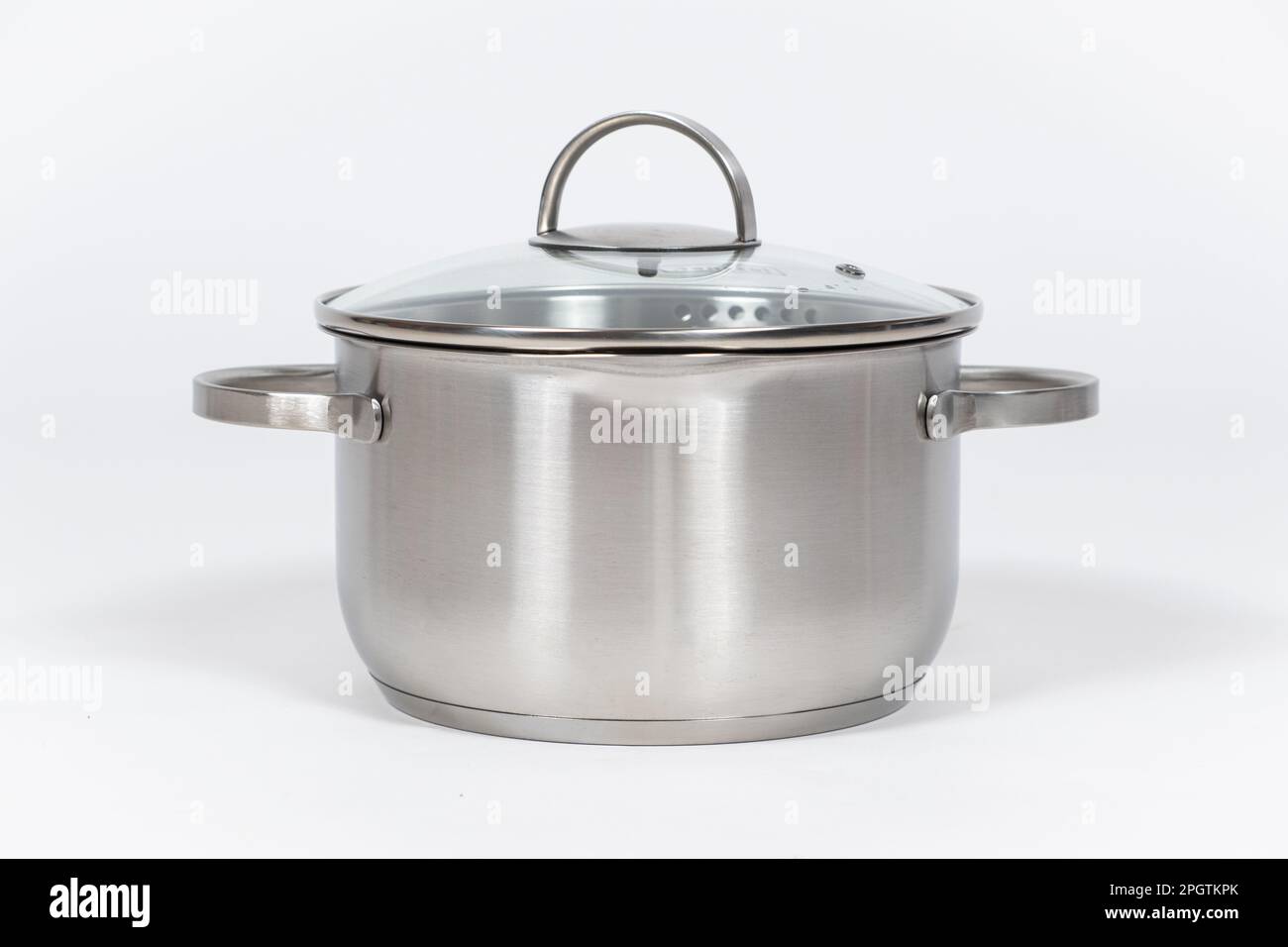 Stainless steel pot with glass lid and drain spout on a white ...