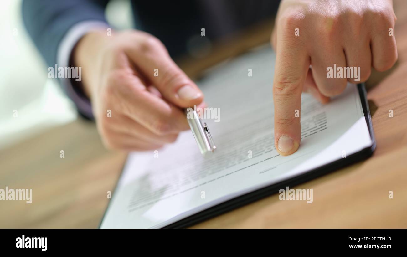 Manager showing client place to sign in document and holding out pen ...