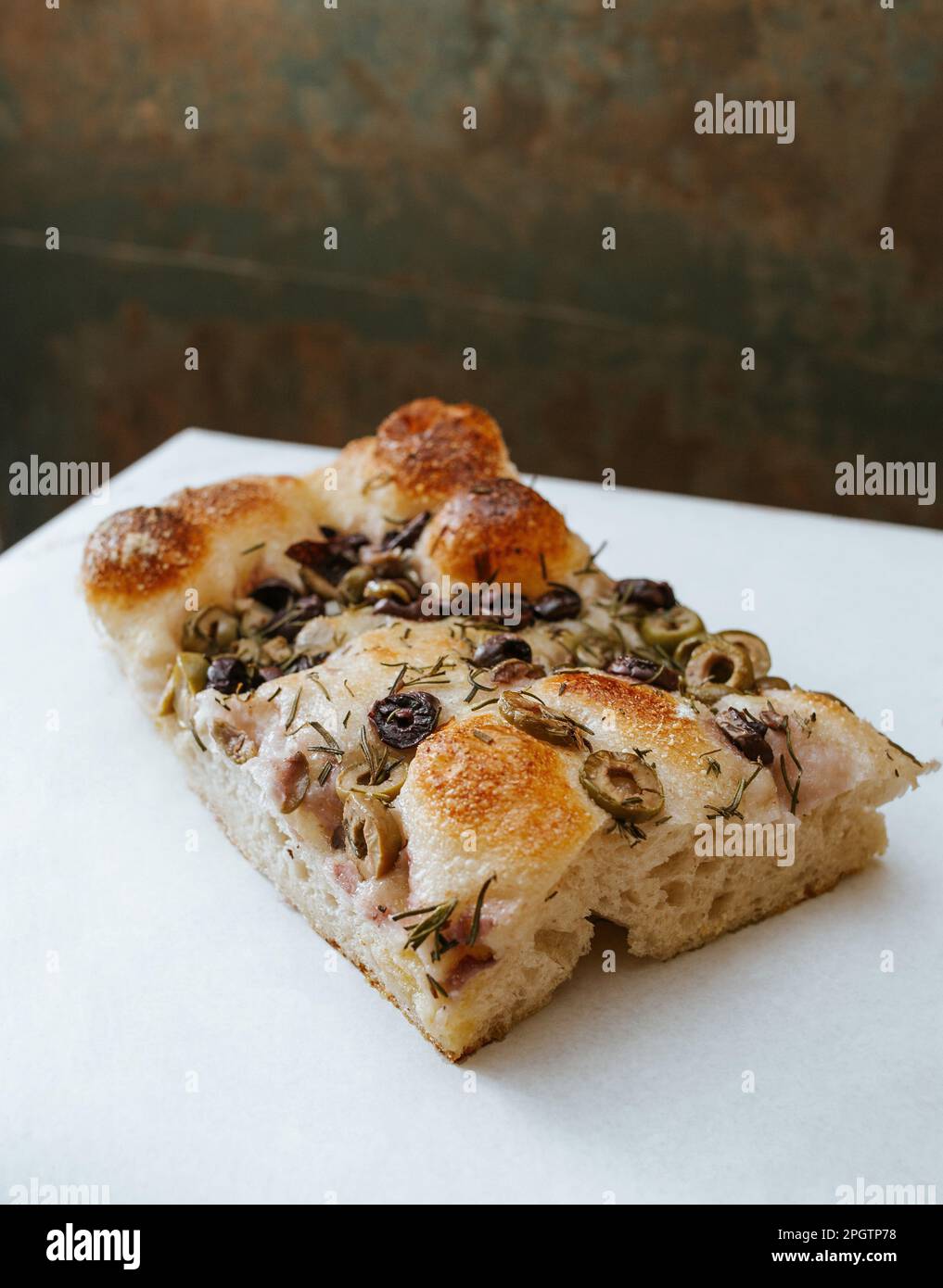 A close-up photo of a freshly baked slice of bread on a white surface ...