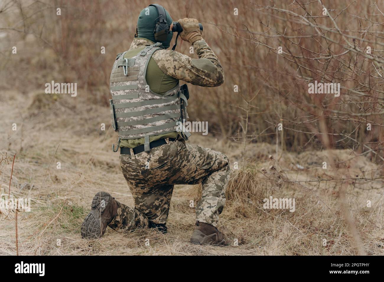 a soldier in camouflage holds binoculars. military man holding ...