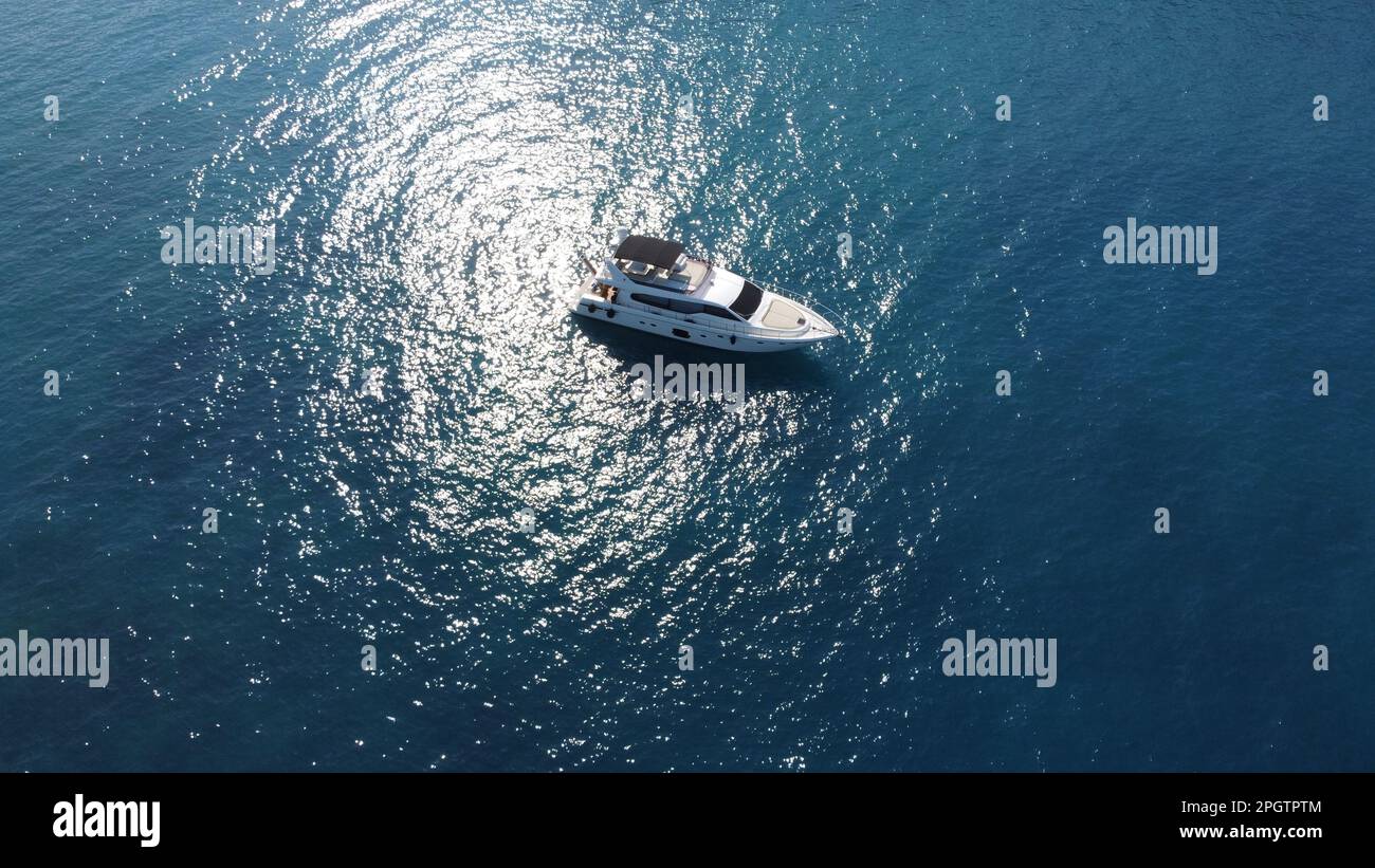 A boat sailing on the ocean with a glistening reflection of the sun ...