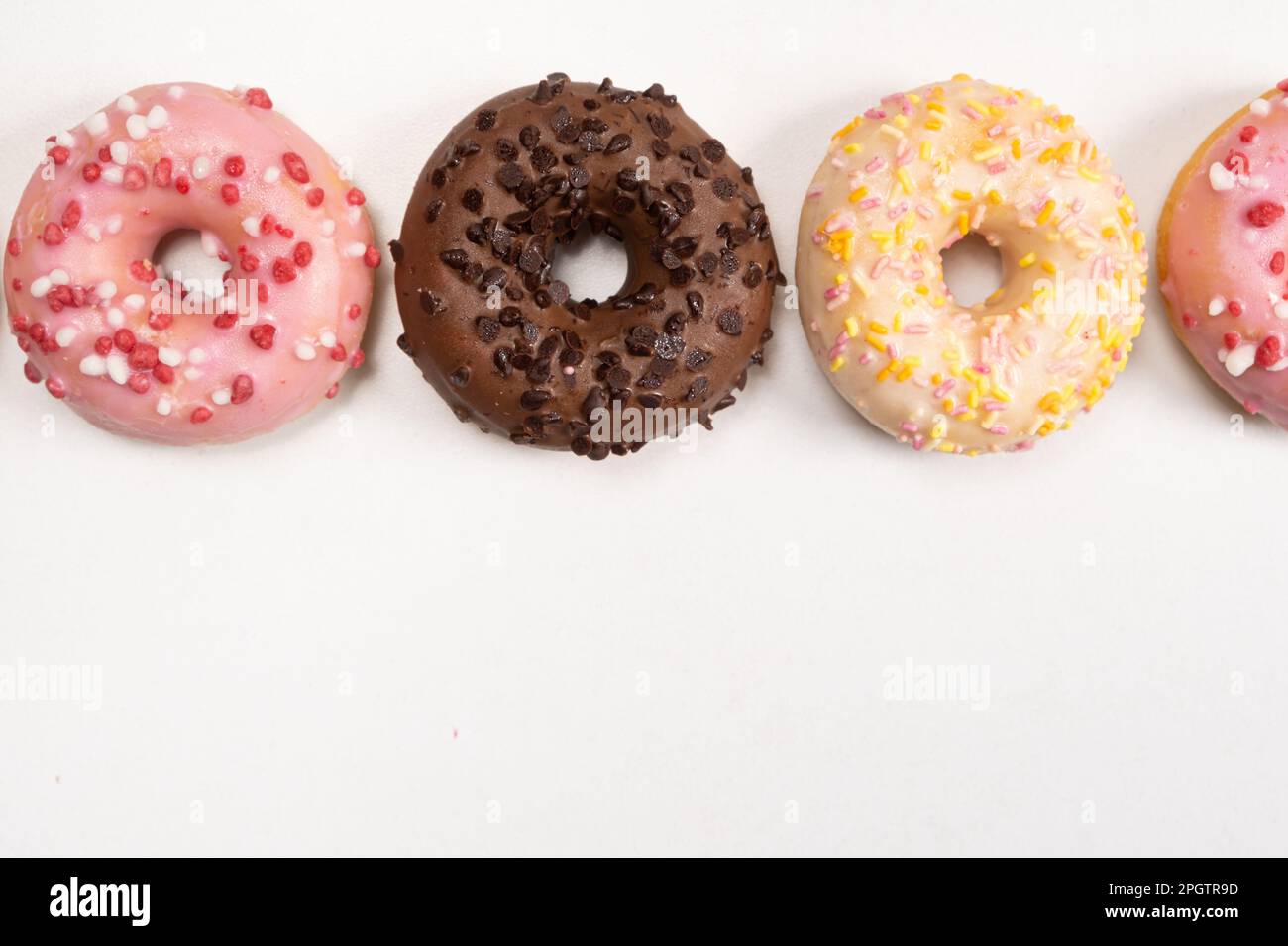 Four donuts in a row - white, pink and chocolate on a white background ...