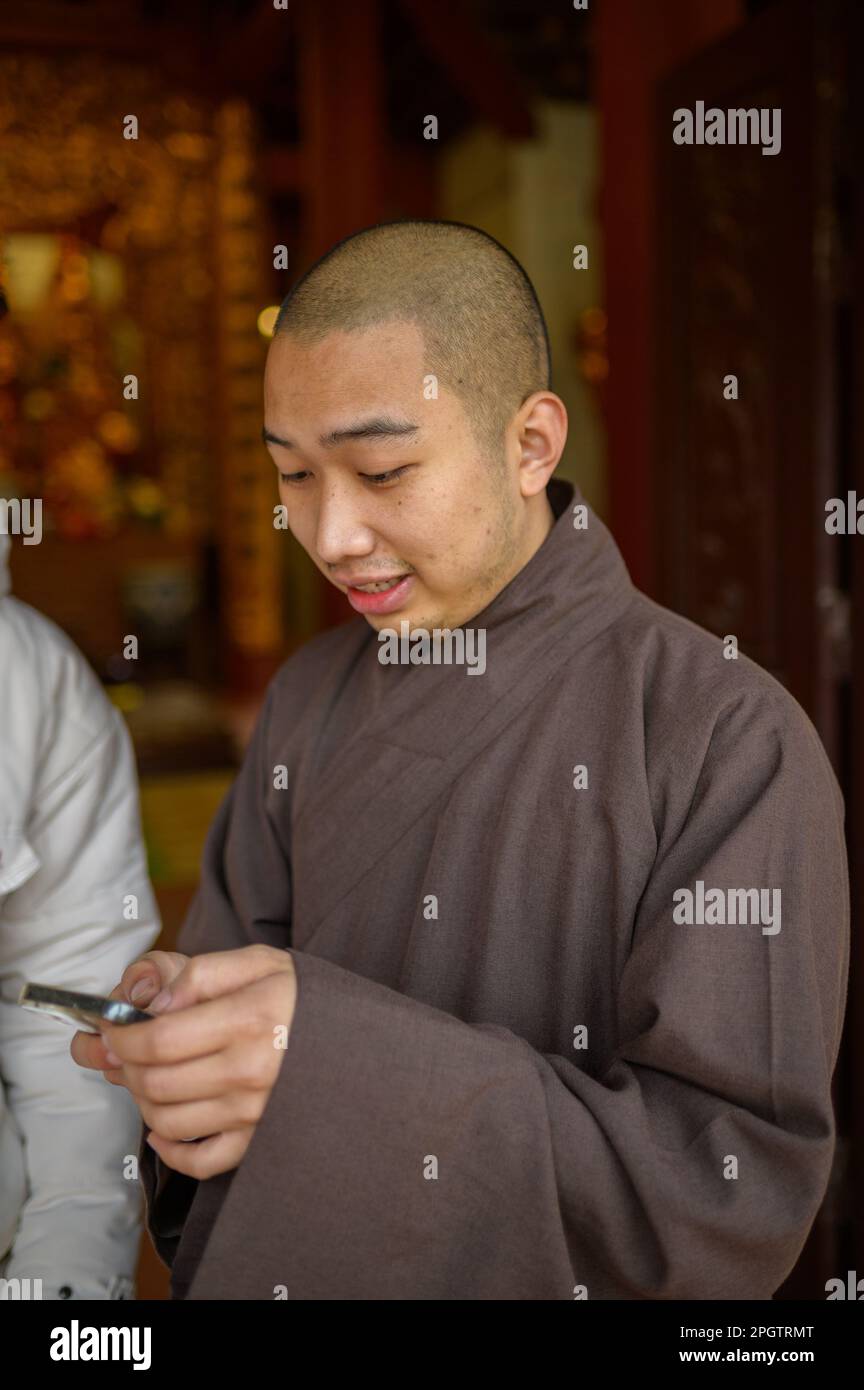 Modern Asian male monk in black garment standing near temple and ...