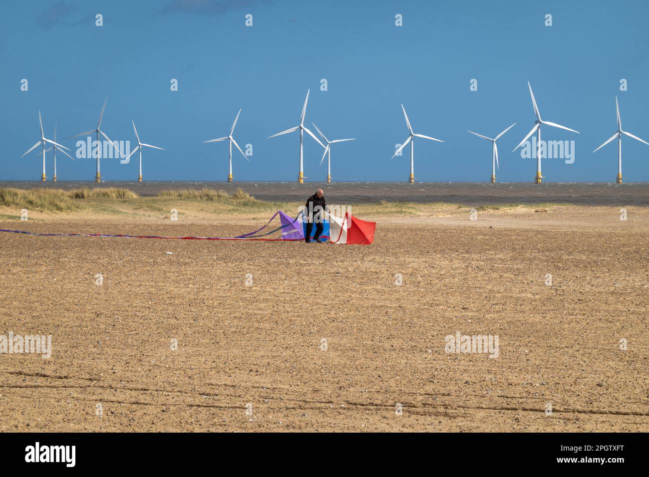 Quad line kite being flown on a beach in Norfolk with wind farm in ...
