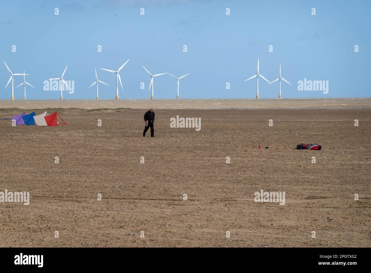 Quad line kite being flown on a beach in Norfolk with wind farm in ...