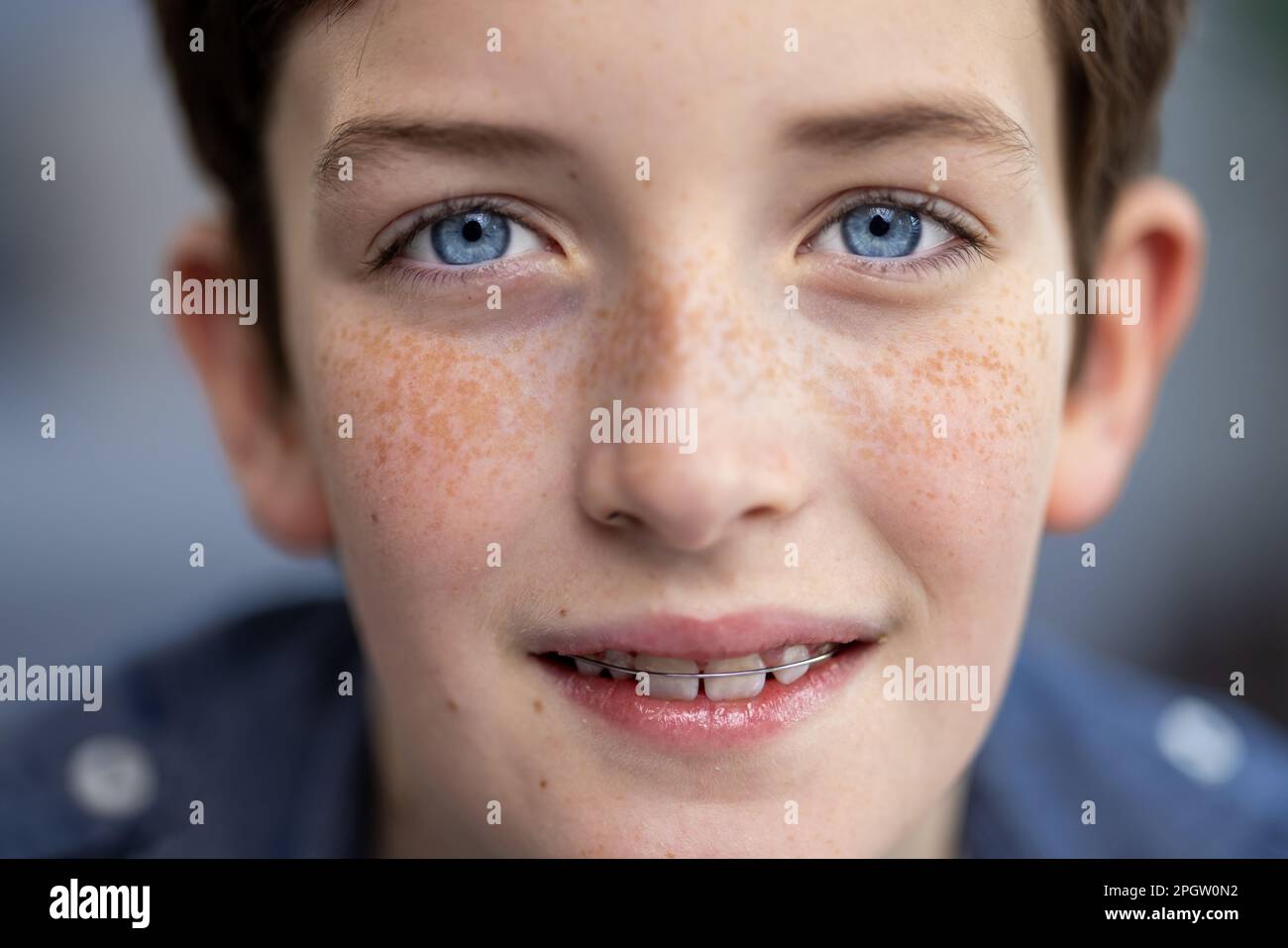 Close-up portrait of a teenage boy with blue eyes and a blue shirt, a ...