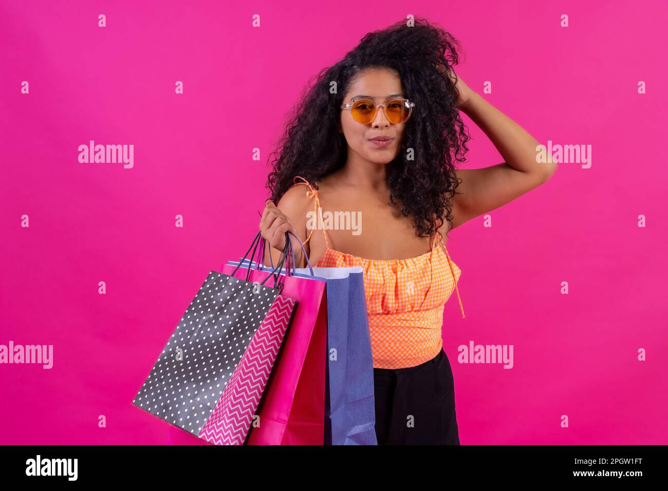 A cheerful Hispanic female with curly hair and an orange top ...