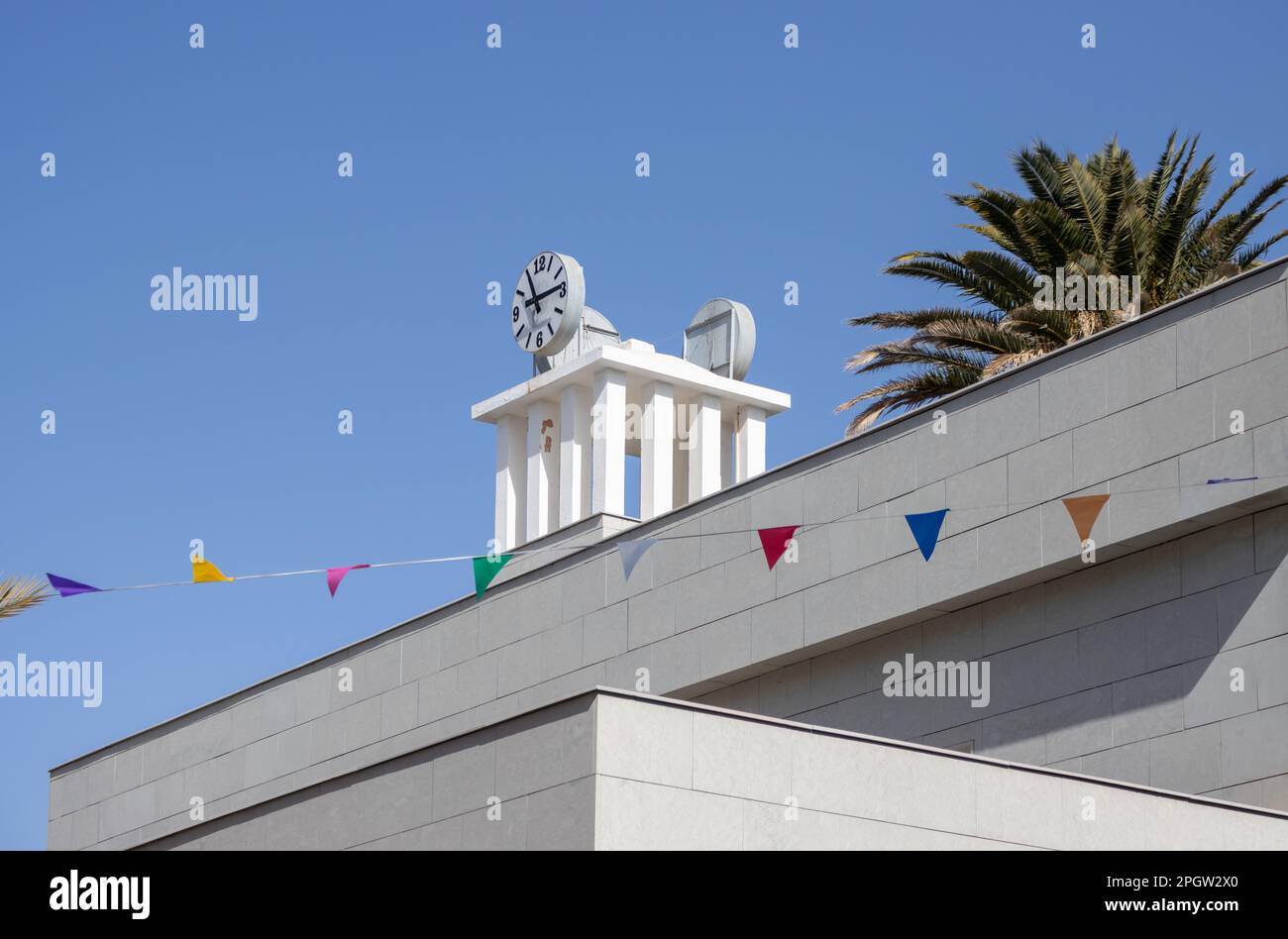 White traditional spanish style building with a tower with clock. Palm ...