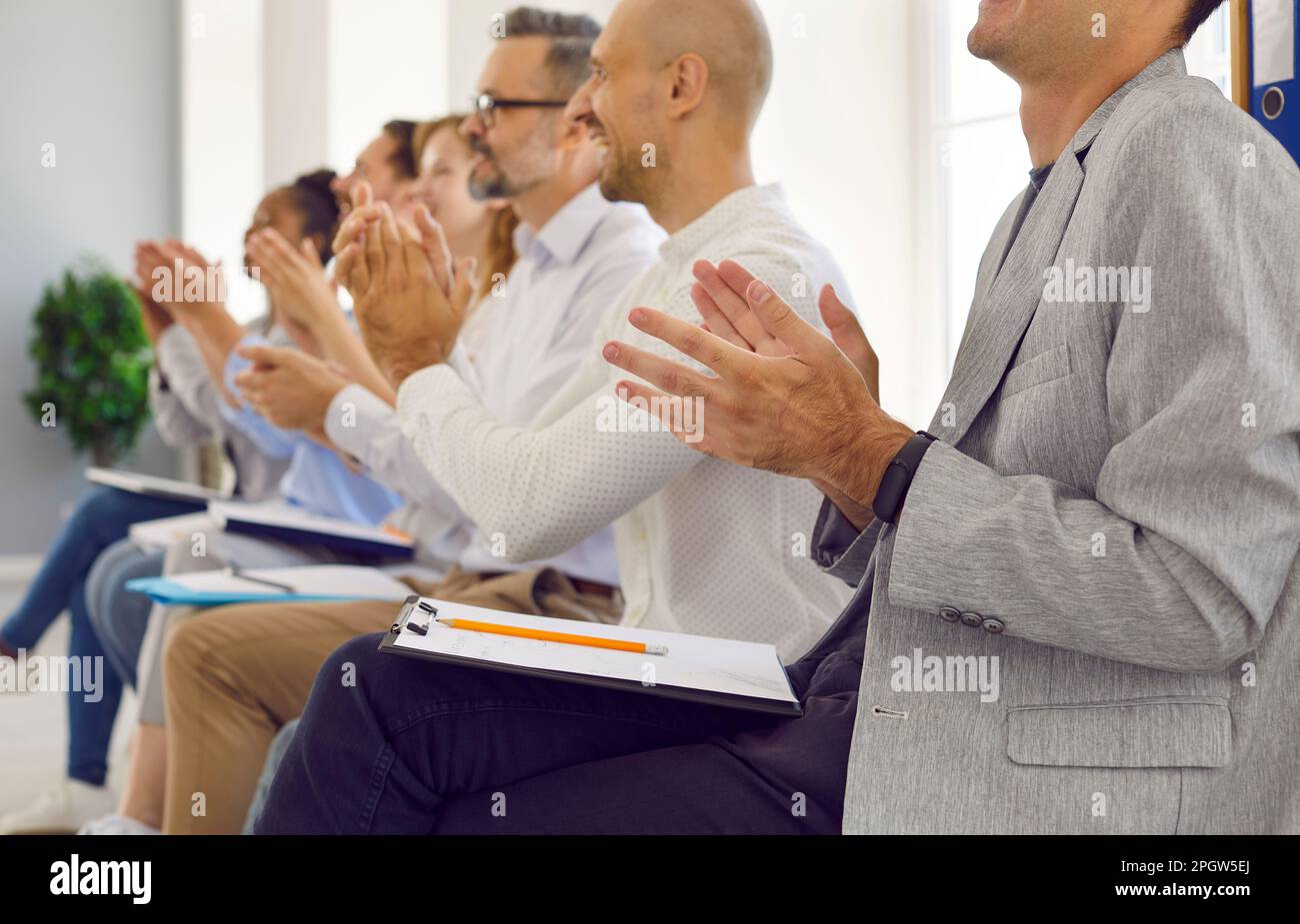 Happy audience clapping hands at professional business conference, workshop or presentation ...