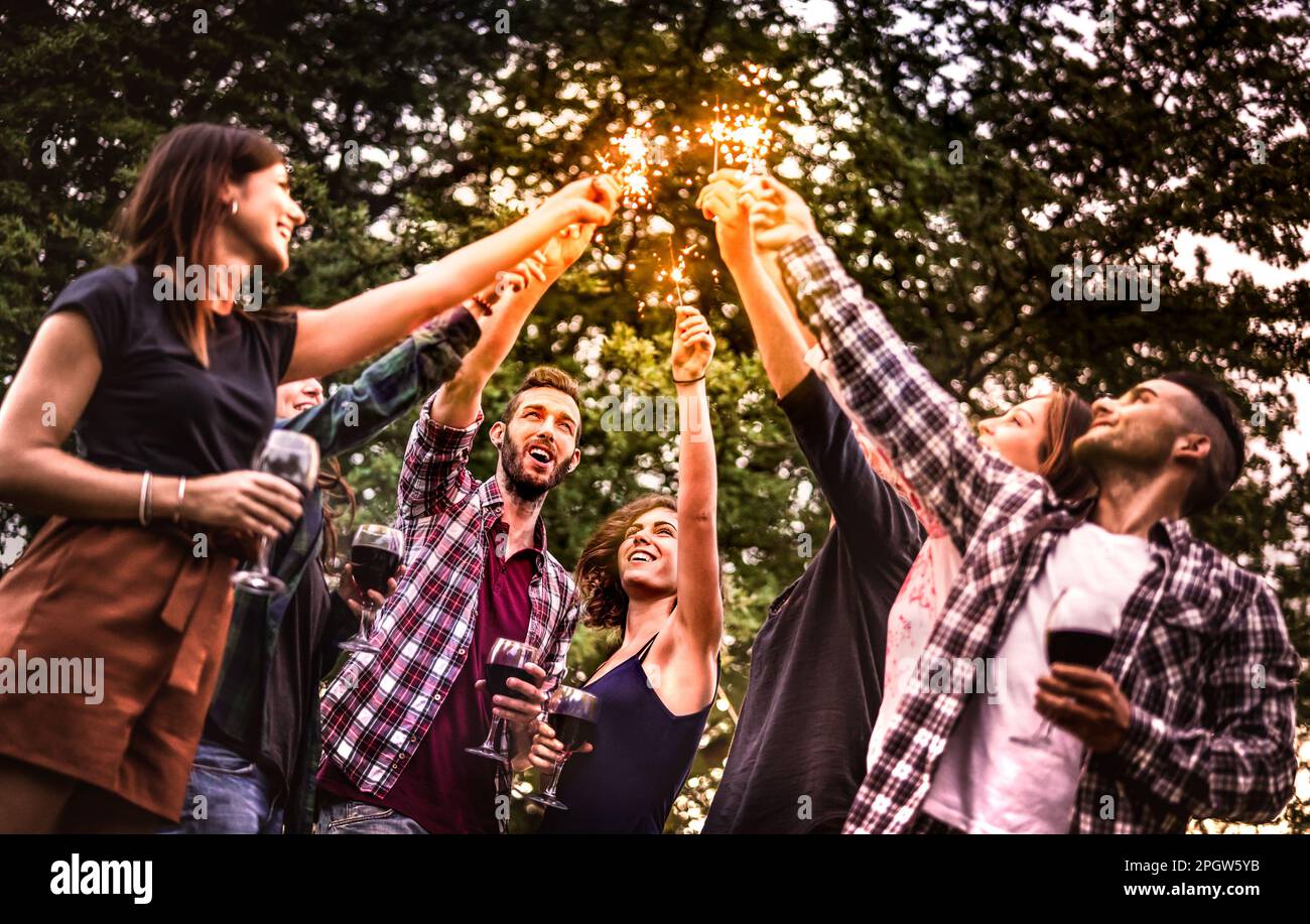 Fancy millenial people having fun with fire sparkles and toasting wine ...