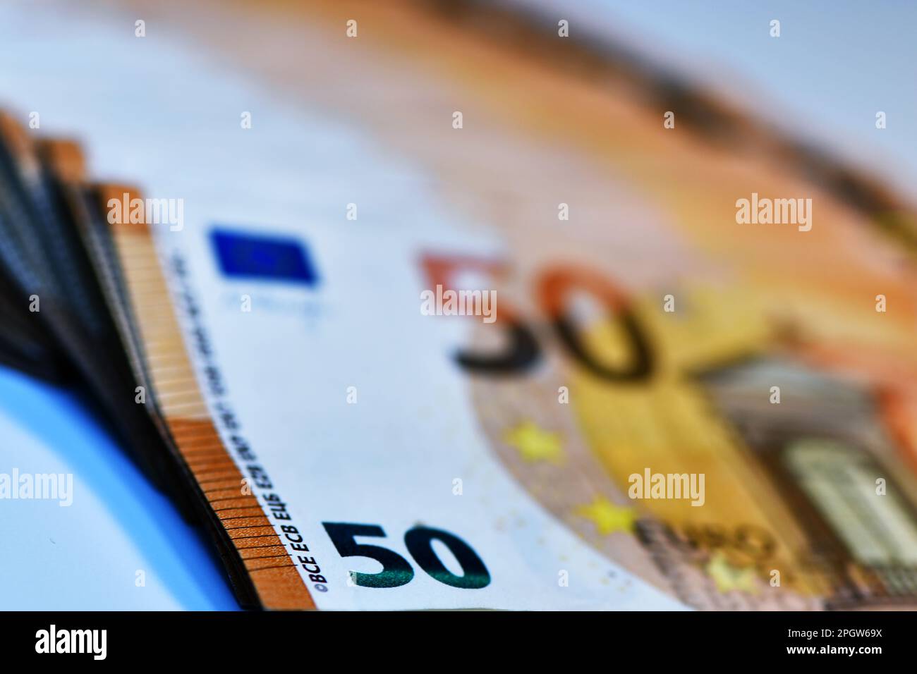 Concept of many euros: a pile of rolled 50-euro bills lying on a white ...