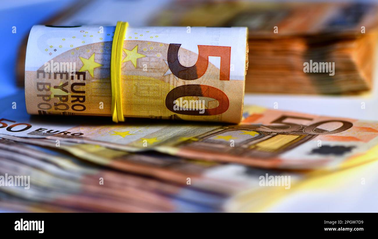 Concept of many euros: a pile of rolled 50-euro bills lying on a white ...