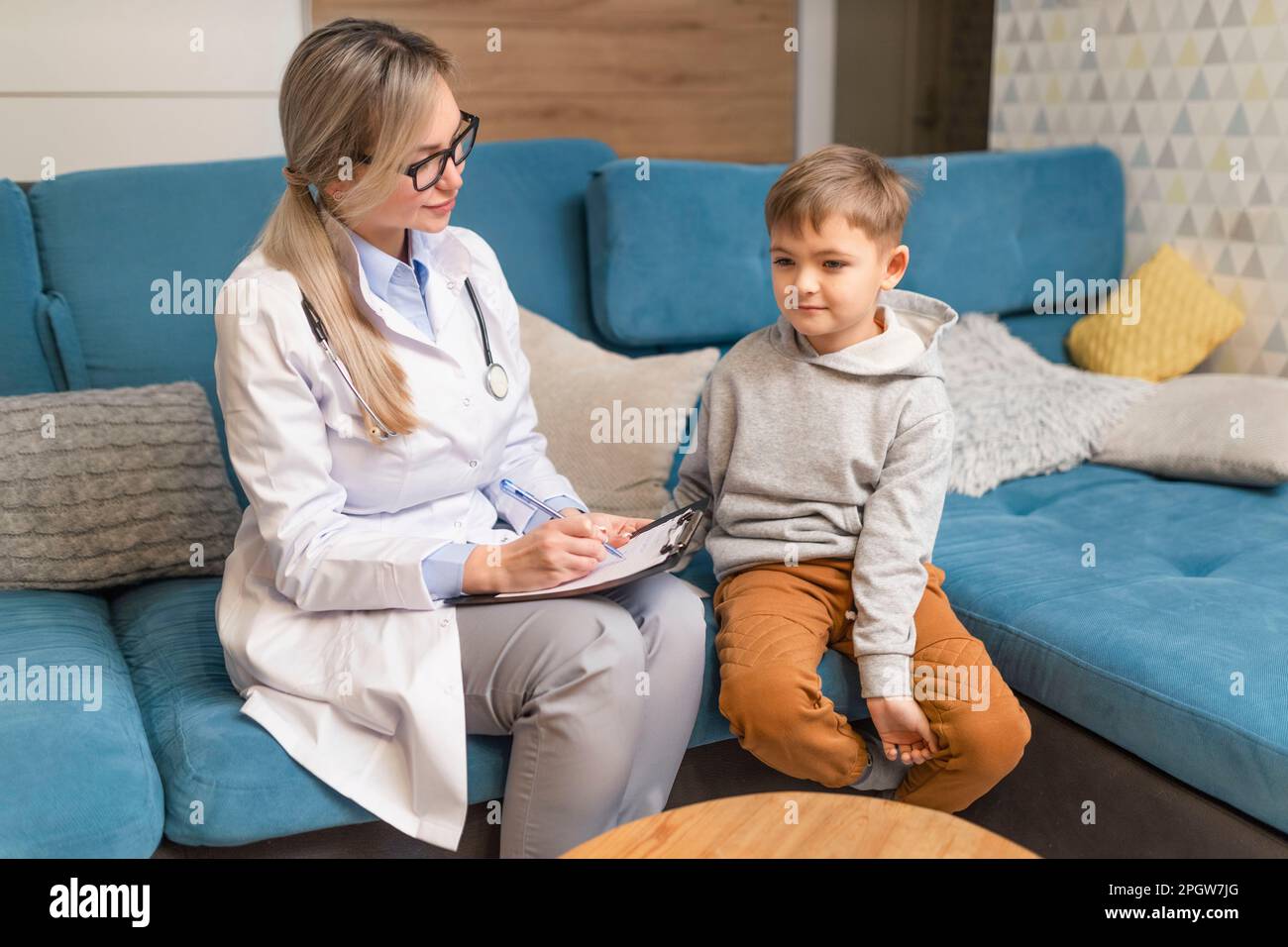 A family doctor examines a little boy at home. Pediatrician girl treats ...