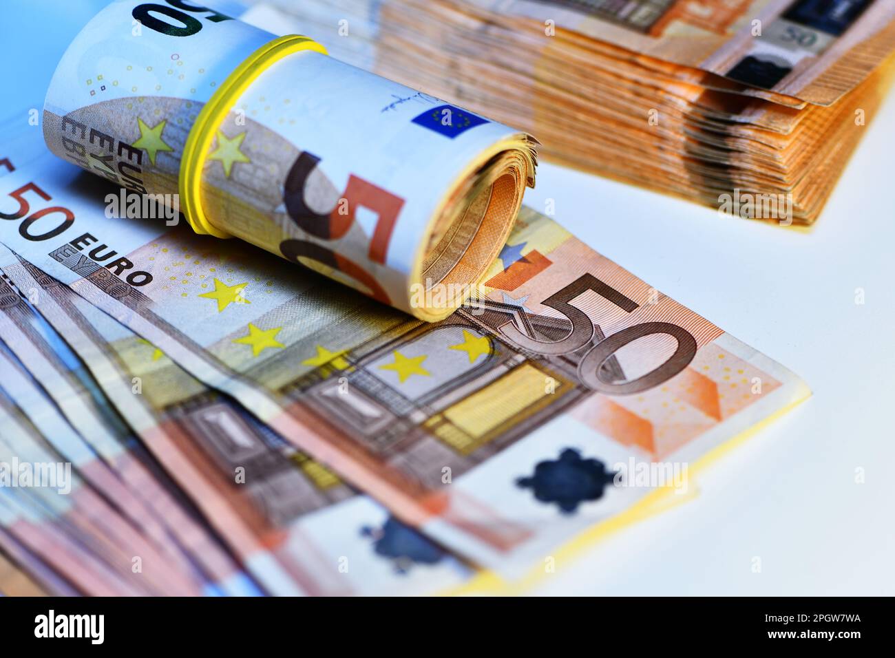 Concept of many euros: a pile of rolled 50-euro bills lying on a white ...