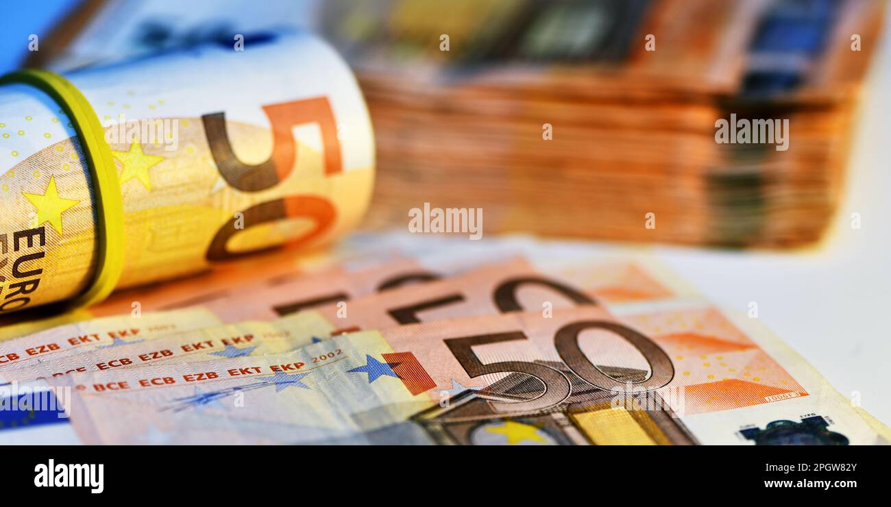 Concept of many euros: a pile of rolled 50-euro bills lying on a white ...