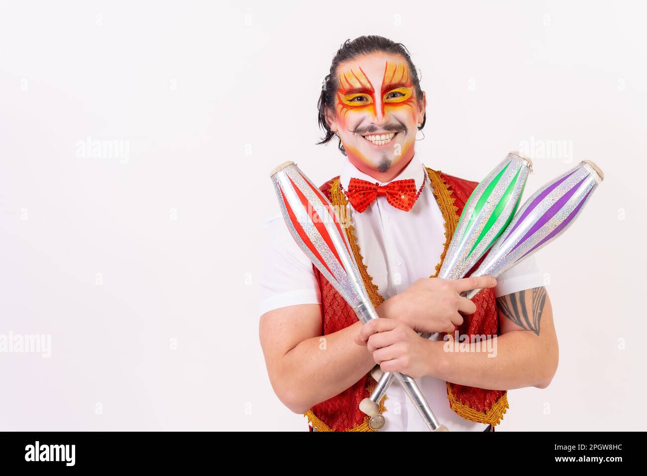 A cheerful circus performer skillfully juggling a number of clubs ...