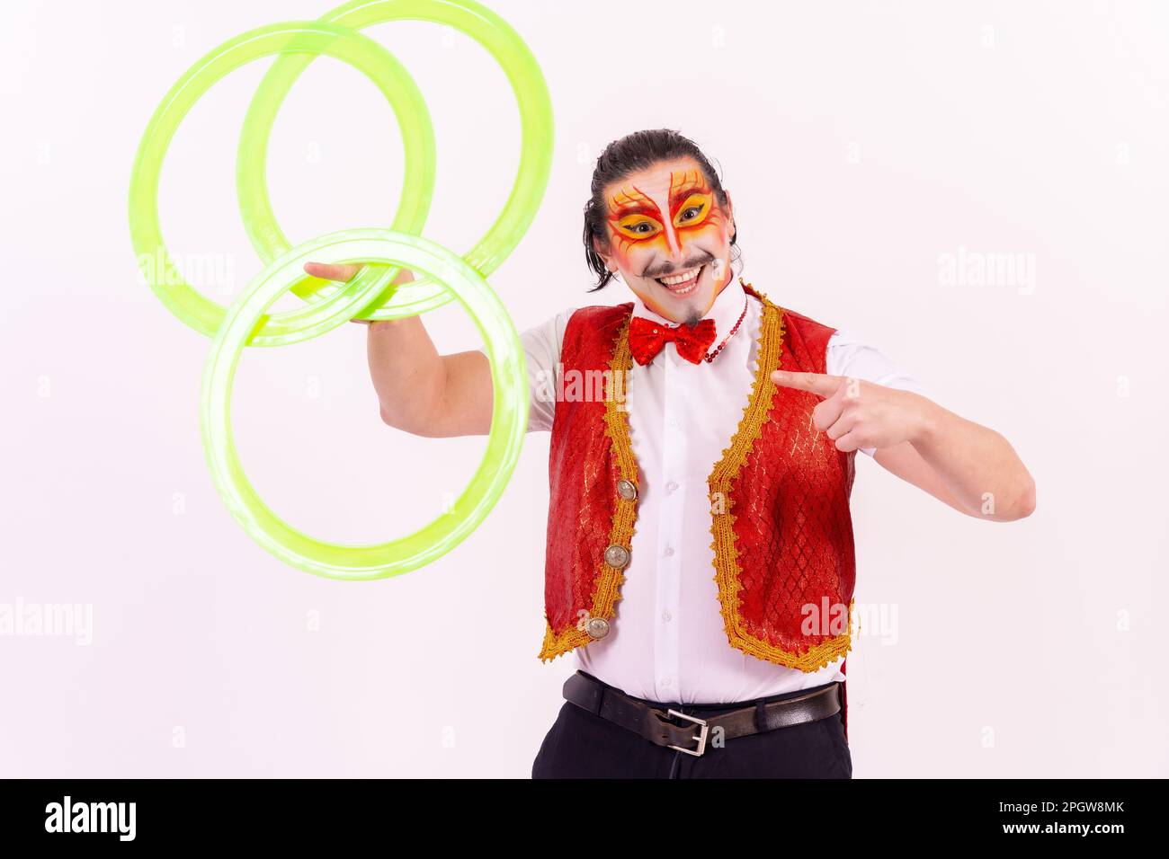 A cheerful circus performer skillfully juggling a number of rings ...