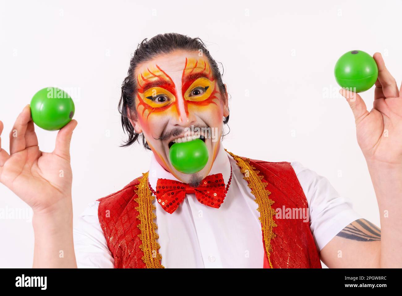 A cheerful circus performer skillfully juggling a number of balls ...