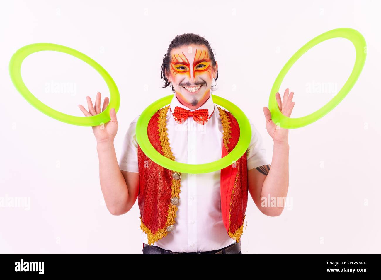 A cheerful circus performer skillfully juggling a number of rings ...