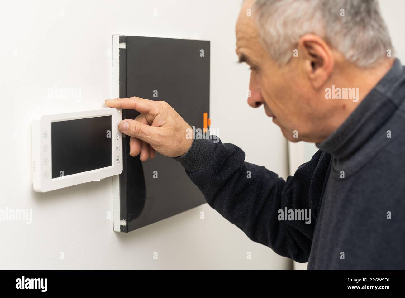 Older man repairing intercom system Stock Photo - Alamy