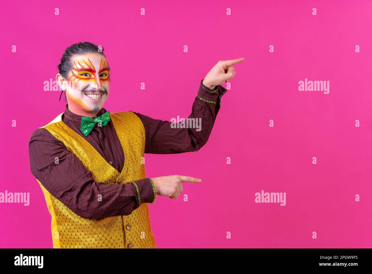 A cheerful circus performer pointing on an empty pink background for ...