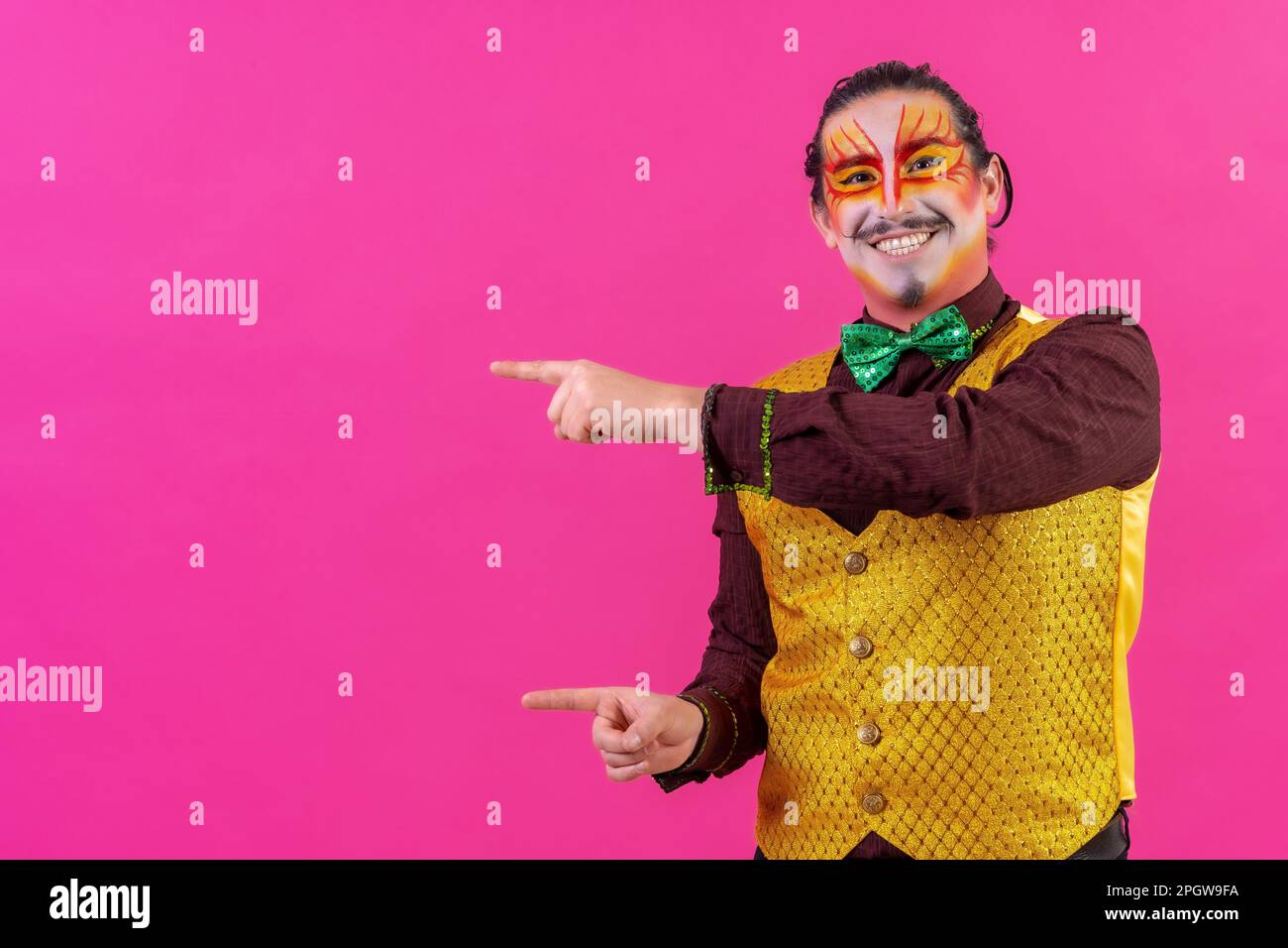 A cheerful circus performer pointing on an empty pink background for ...