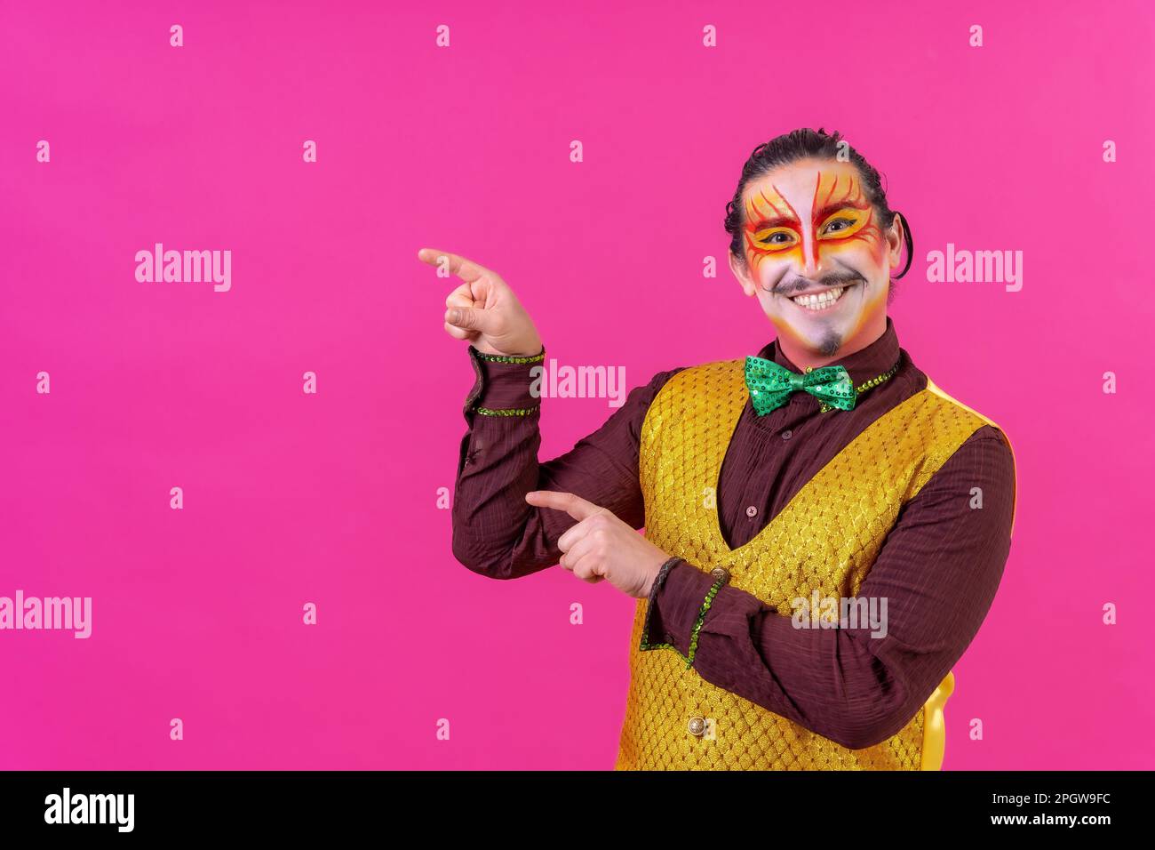 A cheerful circus performer pointing on an empty pink background for ...