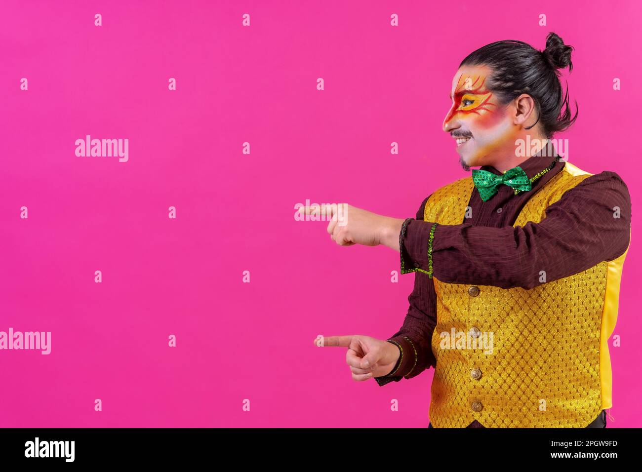 A cheerful circus performer pointing on an empty pink background for ...