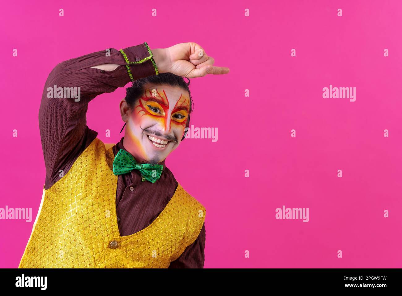 A cheerful circus performer pointing on an empty pink background for ...