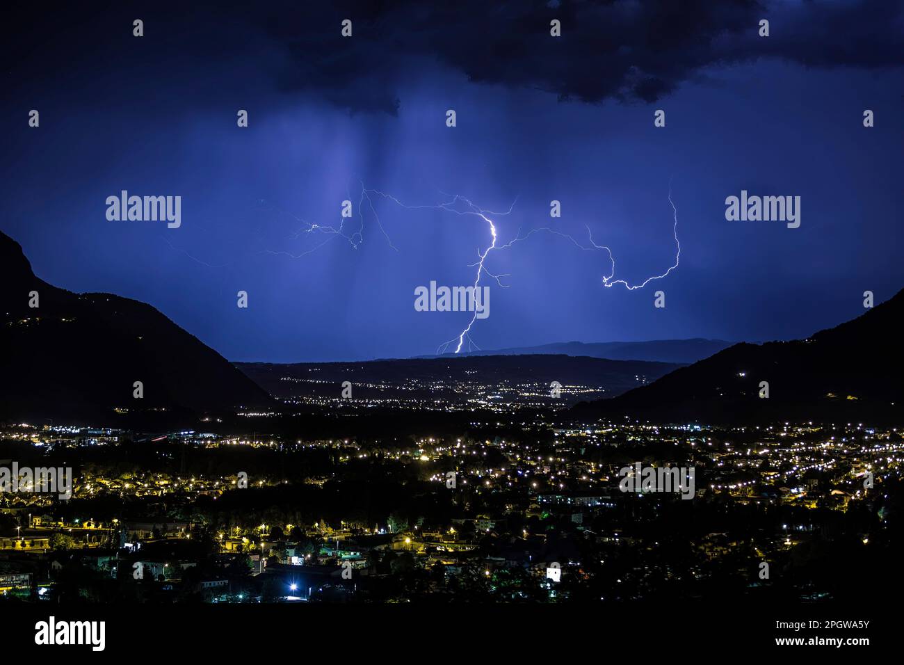 A lightning storm illuminating the night sky above a metropolitan area ...